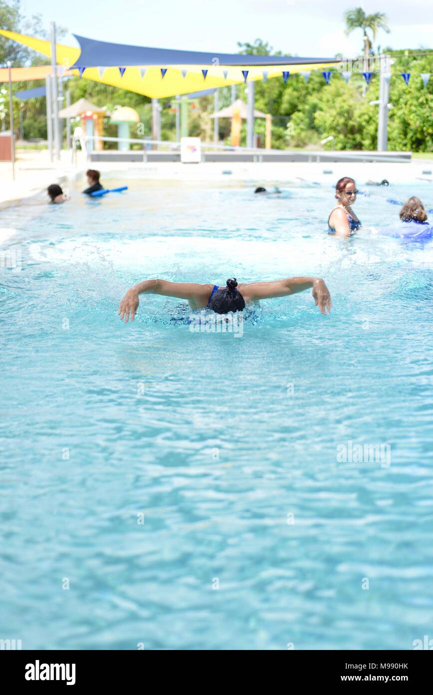 Woman swimming butterfly in a swimming lane at a public pool with other ...