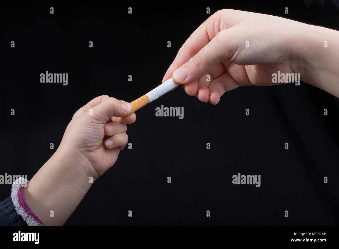Hand is giving out cigarette on a black background Stock Photo - Alamy