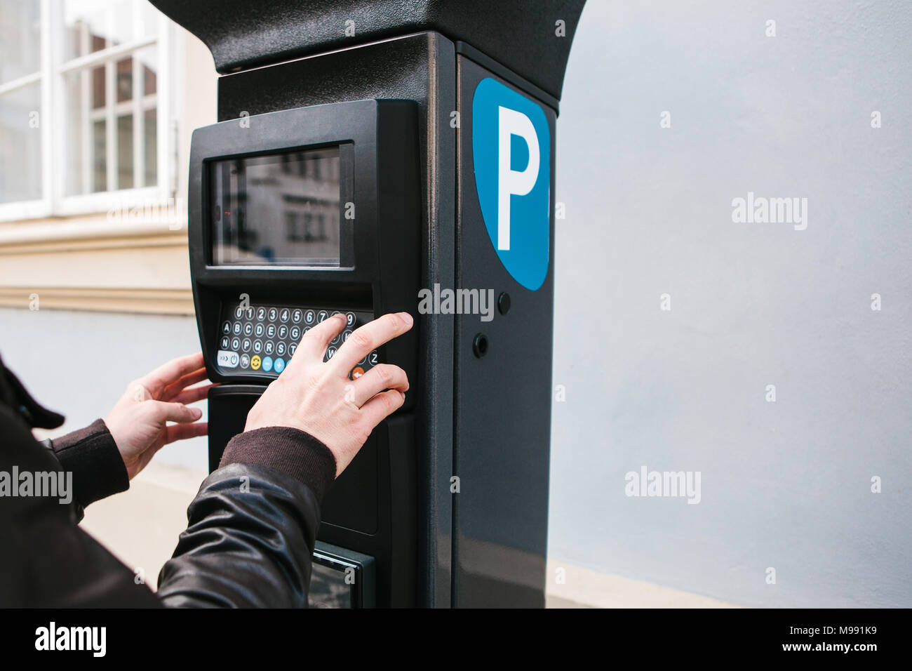 A modern terminal for paying for car parking. The person presses the ...