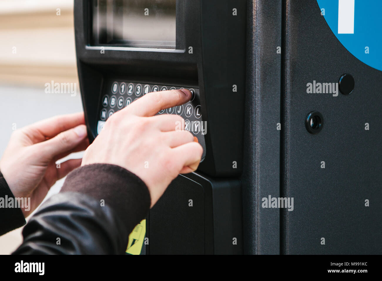 A modern terminal for paying for car parking. The person presses the ...