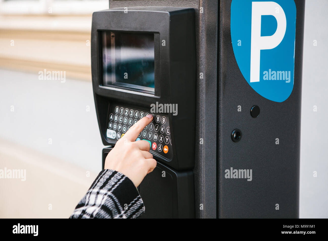 A modern terminal for paying for car parking. The person presses the ...