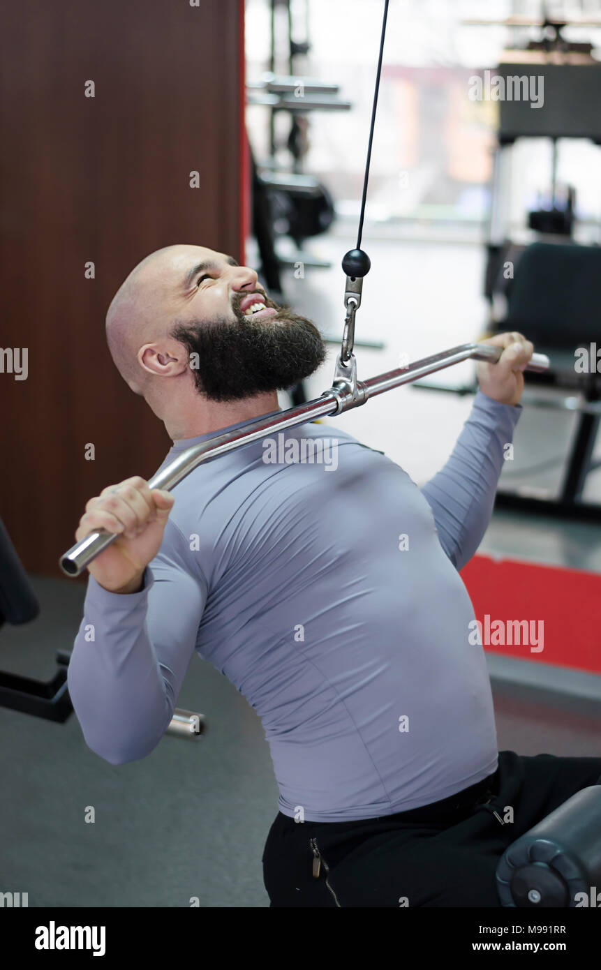 Strained young man working out in the gym, sports exercises for healthy ...