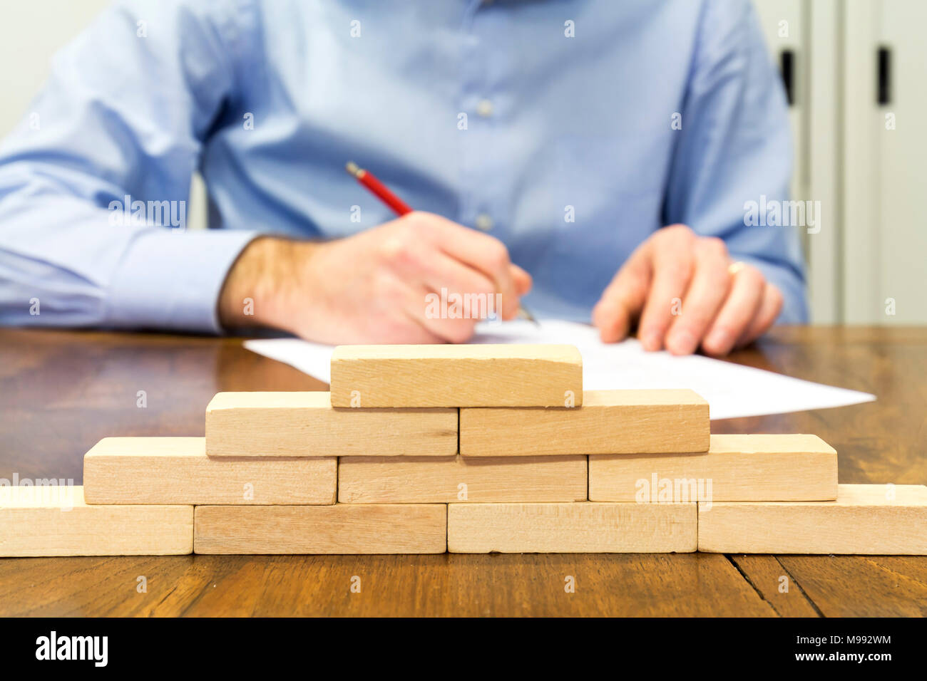 Business man and wall built with small wooden blocks Stock Photo - Alamy