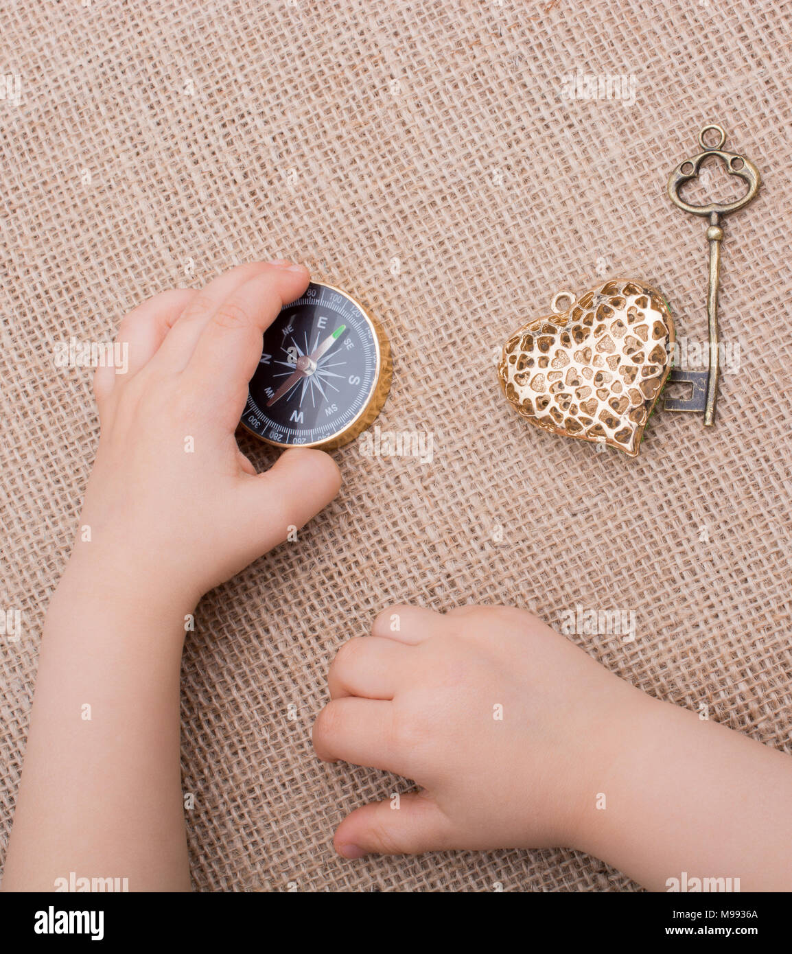 Compass, key and a heart shaped object beside a hand Stock Photo - Alamy