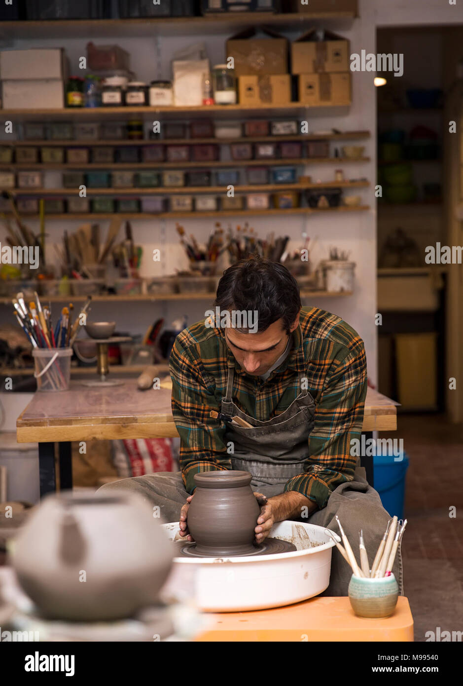 View at an artist makes clay pottery on a spin wheel Stock Photo - Alamy