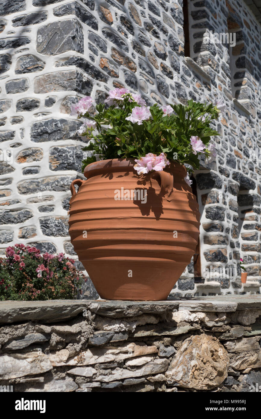 terracotta vase of flowers in front of a stone wall Stock Photo - Alamy