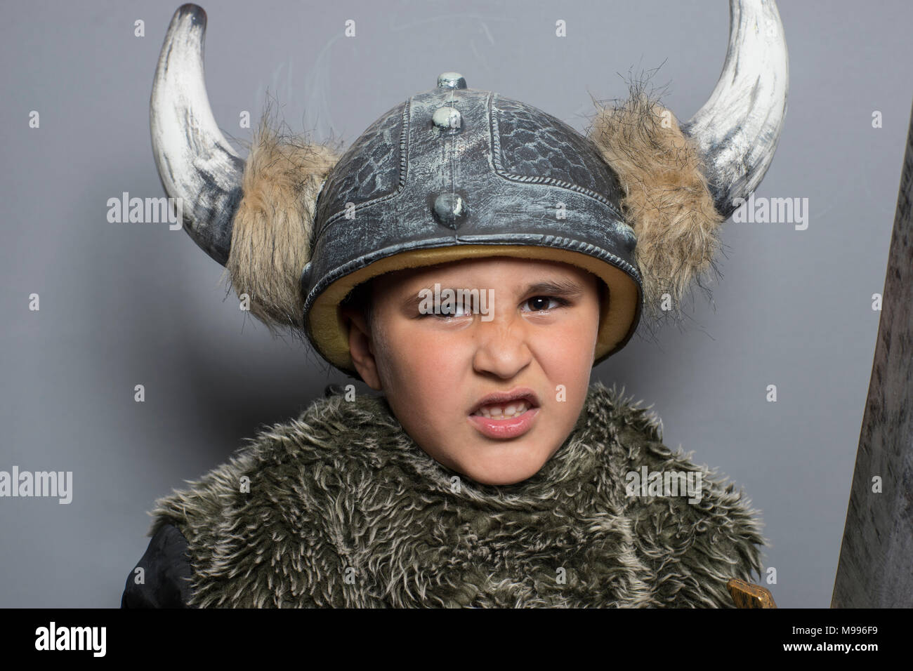 viking brunette boy in fur shirt in preschool age standing indoors ...