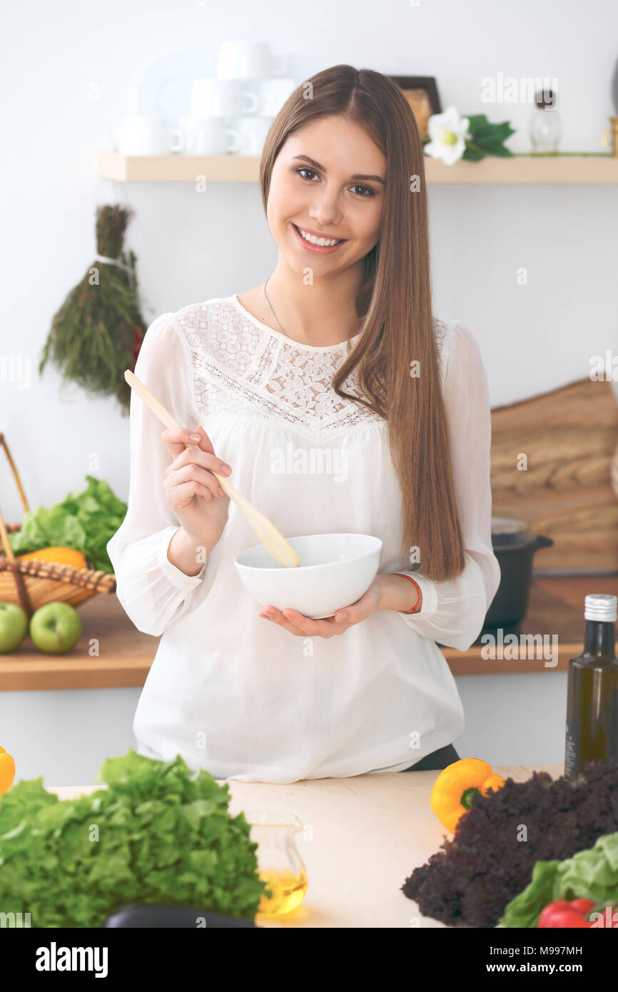 Young happy woman cooking in the kitchen. Healthy meal, lifestyle and ...