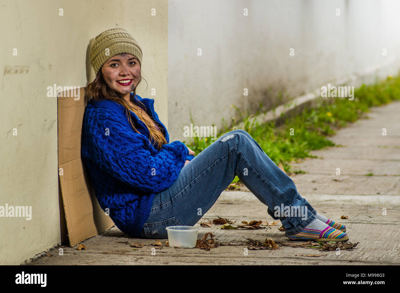Outdoor view of homeless smiling woman begging on the street in cold ...