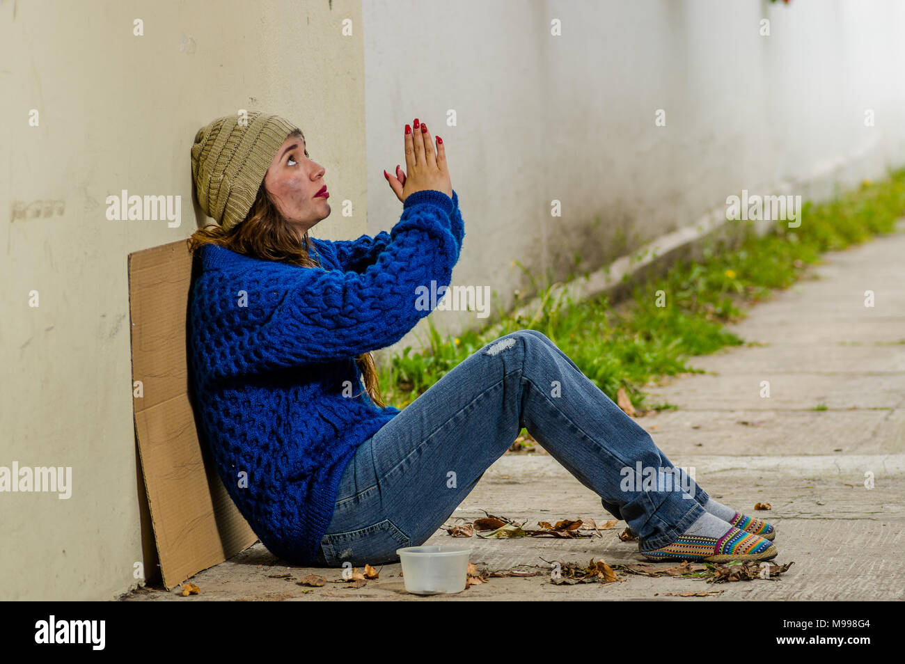 Outdoor view of homeless smiling woman begging on the street in cold ...