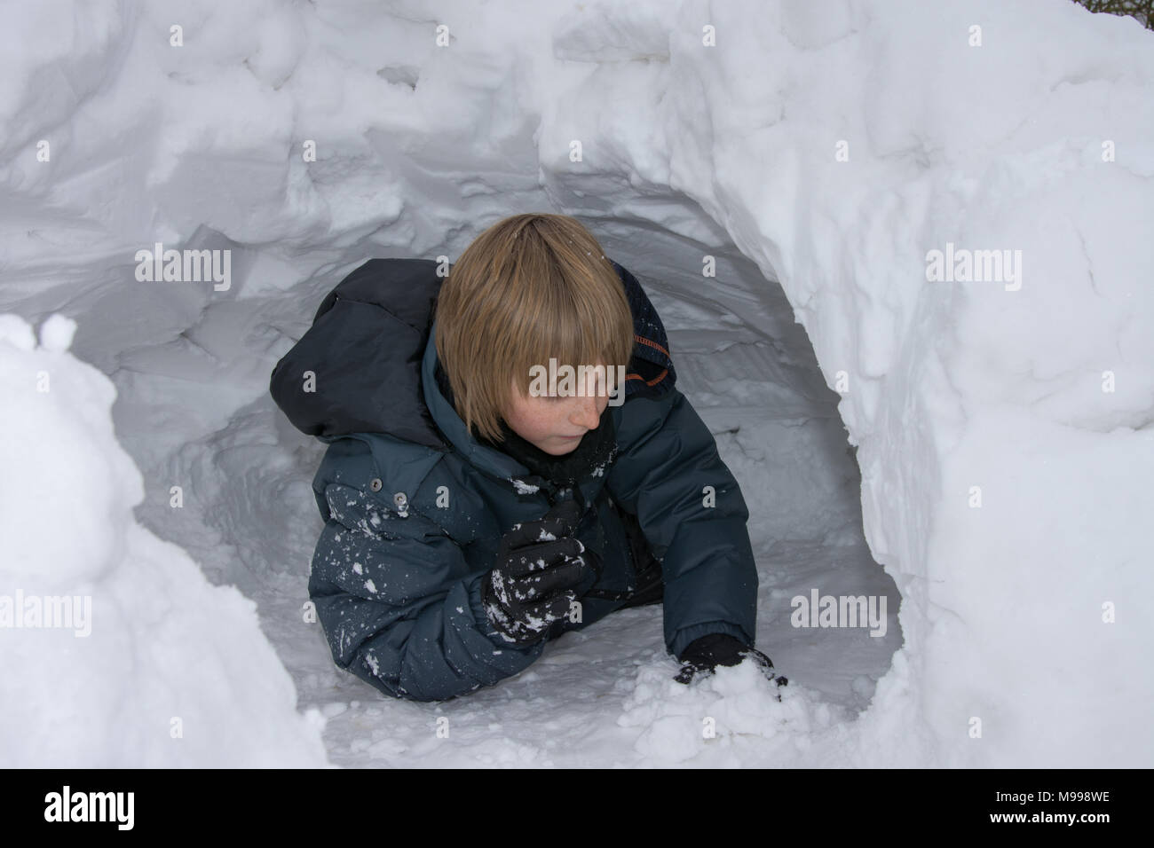 Boy digging snow hole in snow drift Stock Photo - Alamy