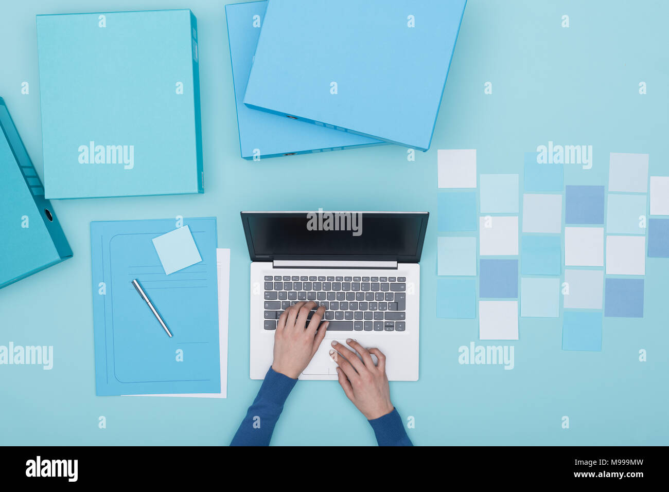 Office worker typing on a laptop, files and sticky notes: creative ...