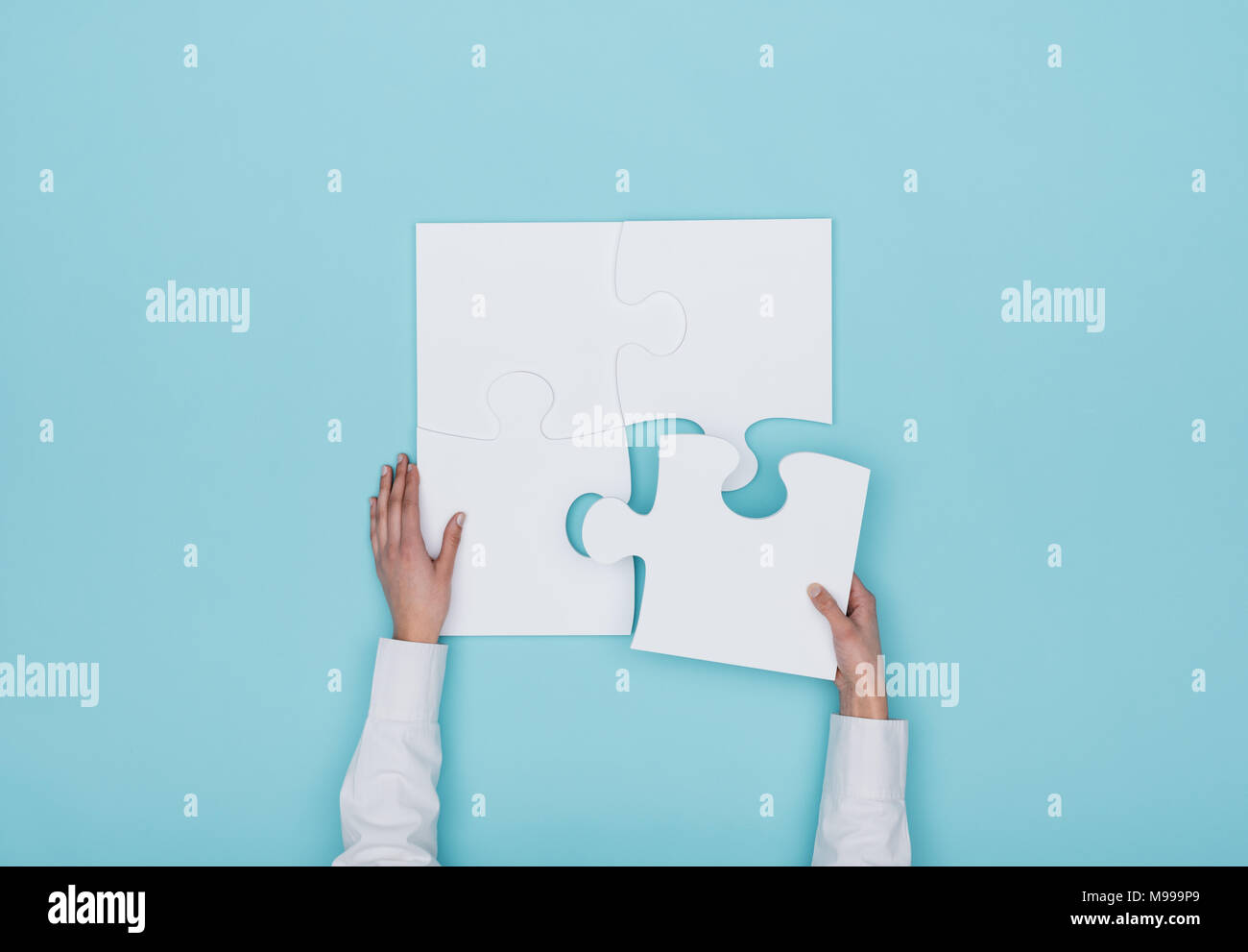 Woman assembling a jigsaw puzzle she is adding the last missing piece ...