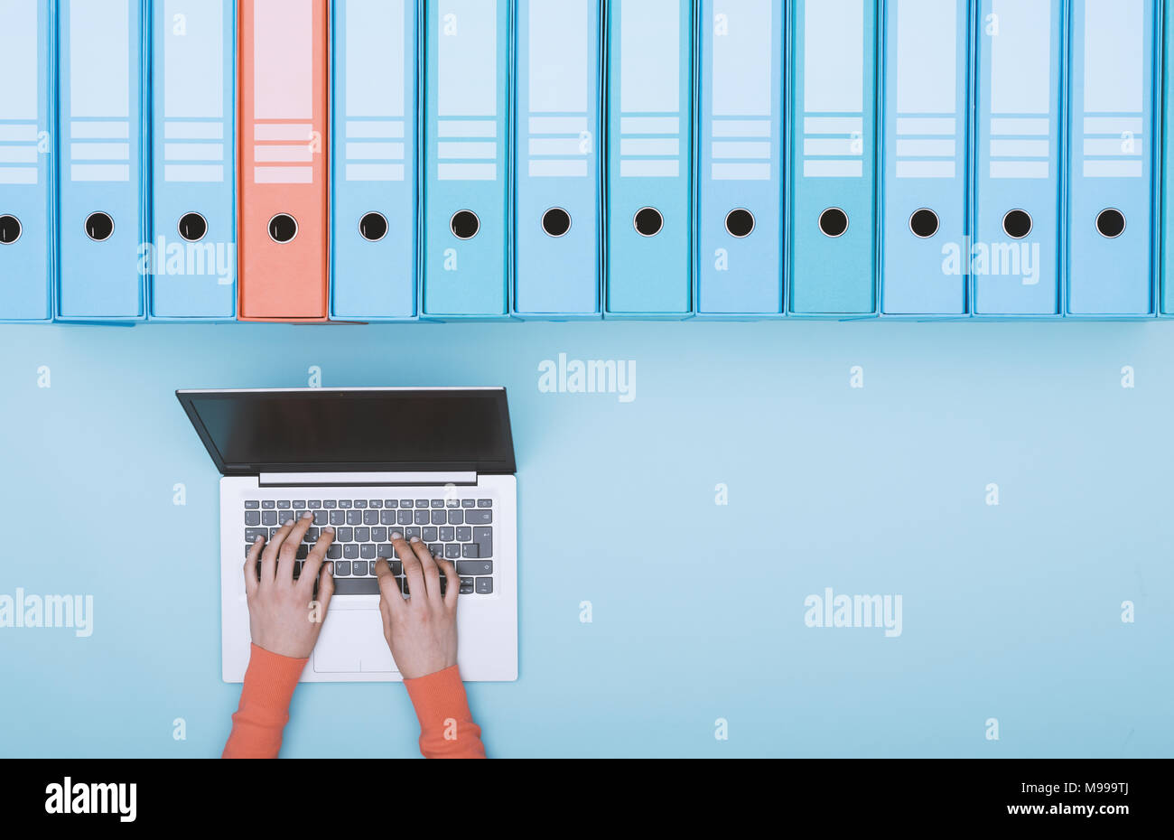 Organized archive with ring binders and woman searching for files in ...