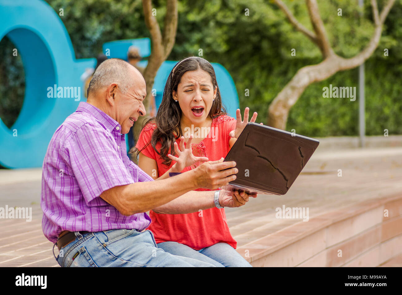 Outdoor view of father holding and computer and sacry daugher screaming ...