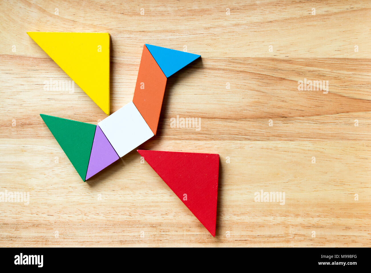 Color tangram puzzle in flying bird shape on wood background Stock ...