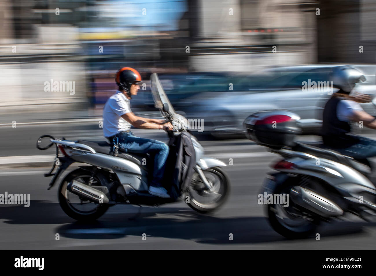Motorcycle riders speeding along busy road in Rome captured to show ...