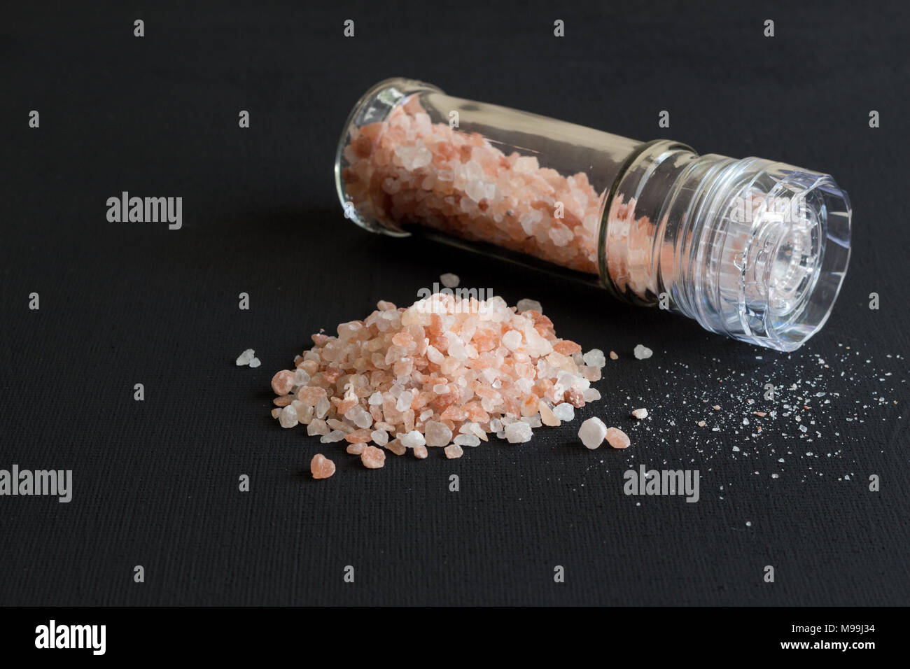 Salt on black background with commercial salt grinder and heap of pink ...