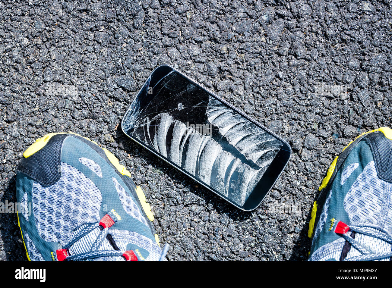 Looking down on asphalt pavement road with broken phone smartphone ...