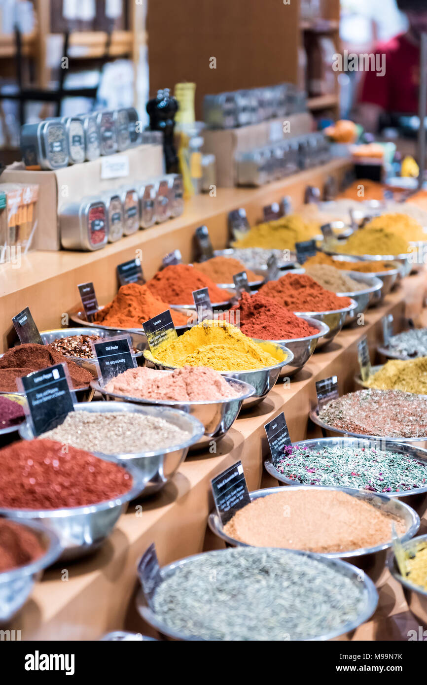 Many spices on display in bowls trays filled with herbs, signs, tea ...