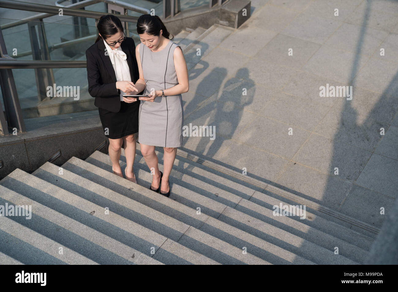 Two asian office lady in formal dress using watching the tablet on the ...