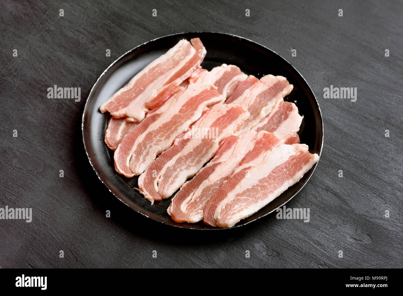 Bacon ready for cooking on black stone background, close up view Stock ...