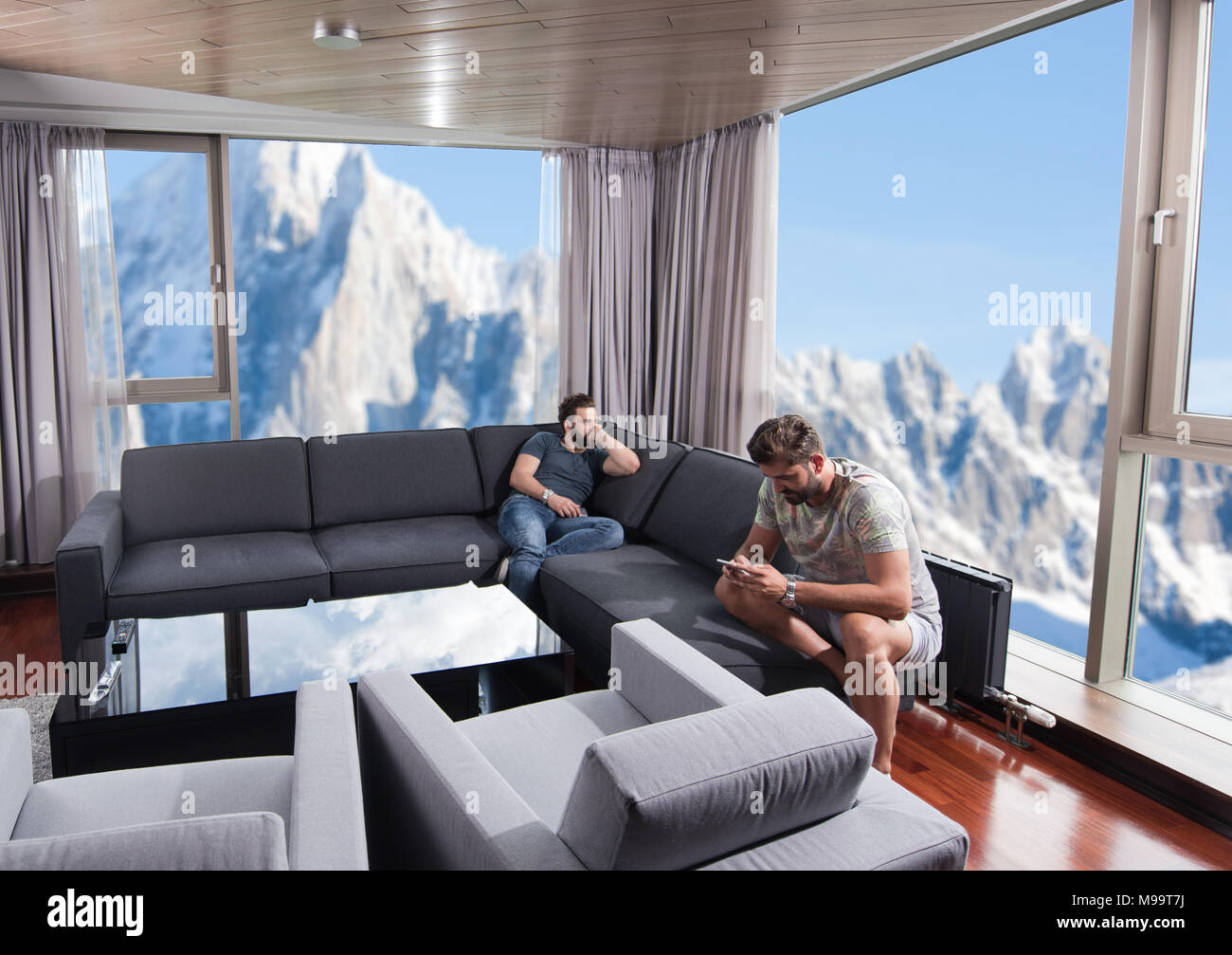 Handsome casual young men using a mobile phones near the window at home ...