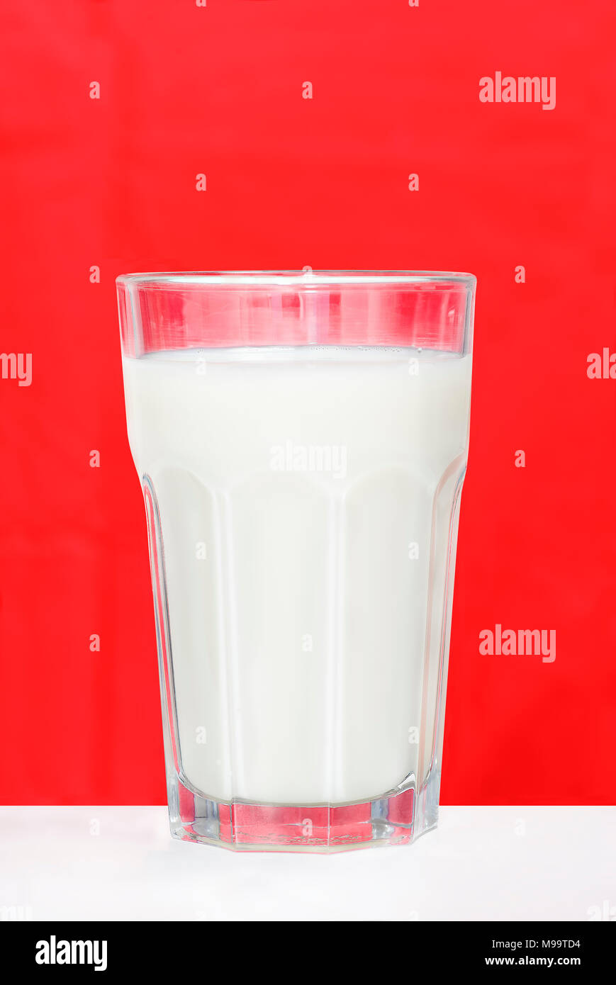 Glass of milk over a red background Stock Photo - Alamy