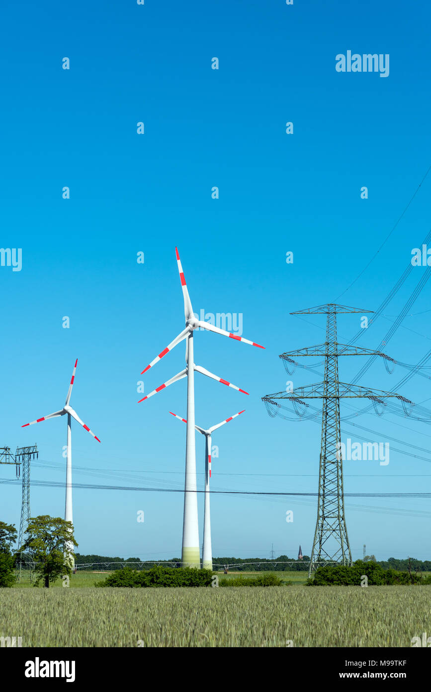 Overhead lines and wind engines on a sunny day seen in Germany Stock ...