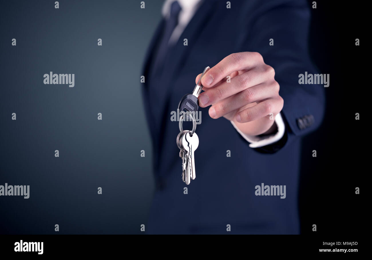 Young businessman hand over keys with empty dark background Stock Photo ...