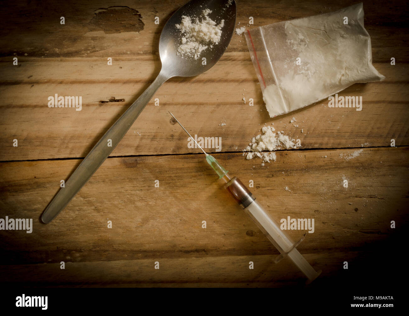 Drugs, powder, syringe and spoon on rustic wooden floor background ...