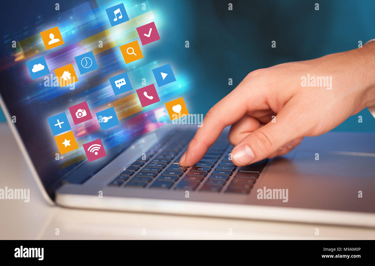 Hand using laptop with colorful fast moving application icons and ...