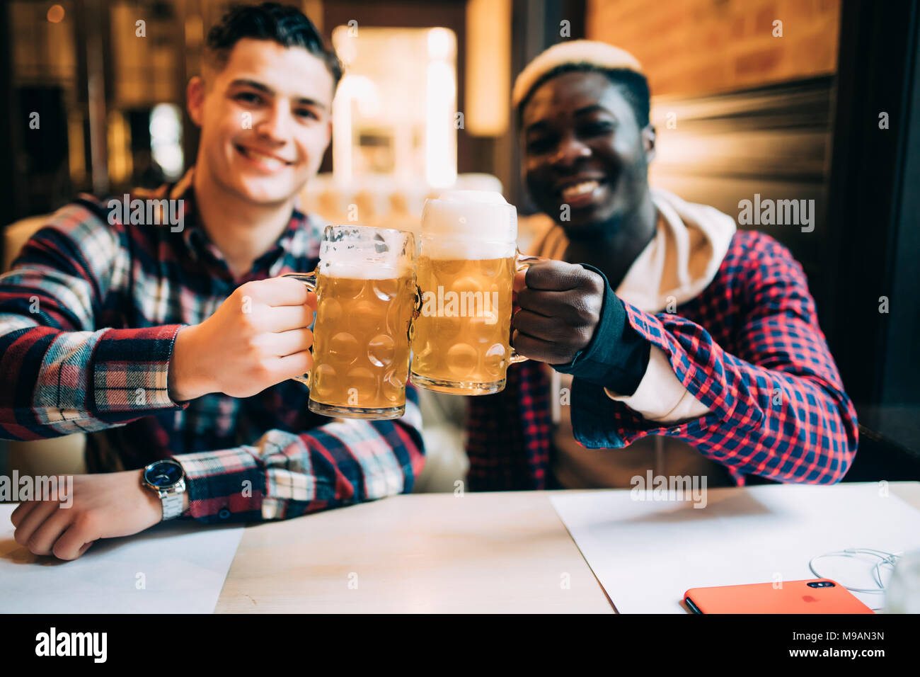 Two best friends or college mates having beer in pub. Afro American man ...