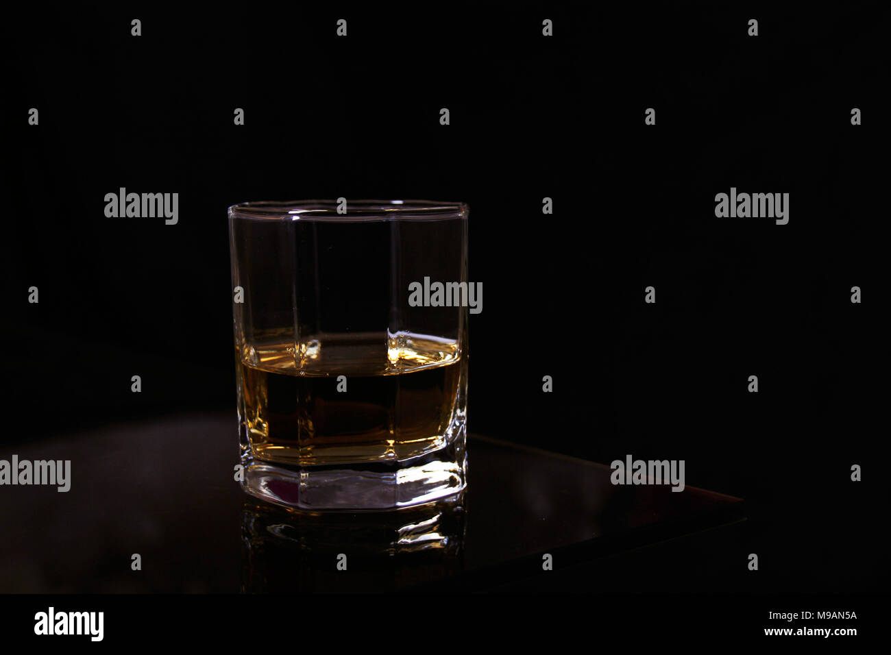 A beautiful and transparent glass of alcoholic drink on a glass table ...