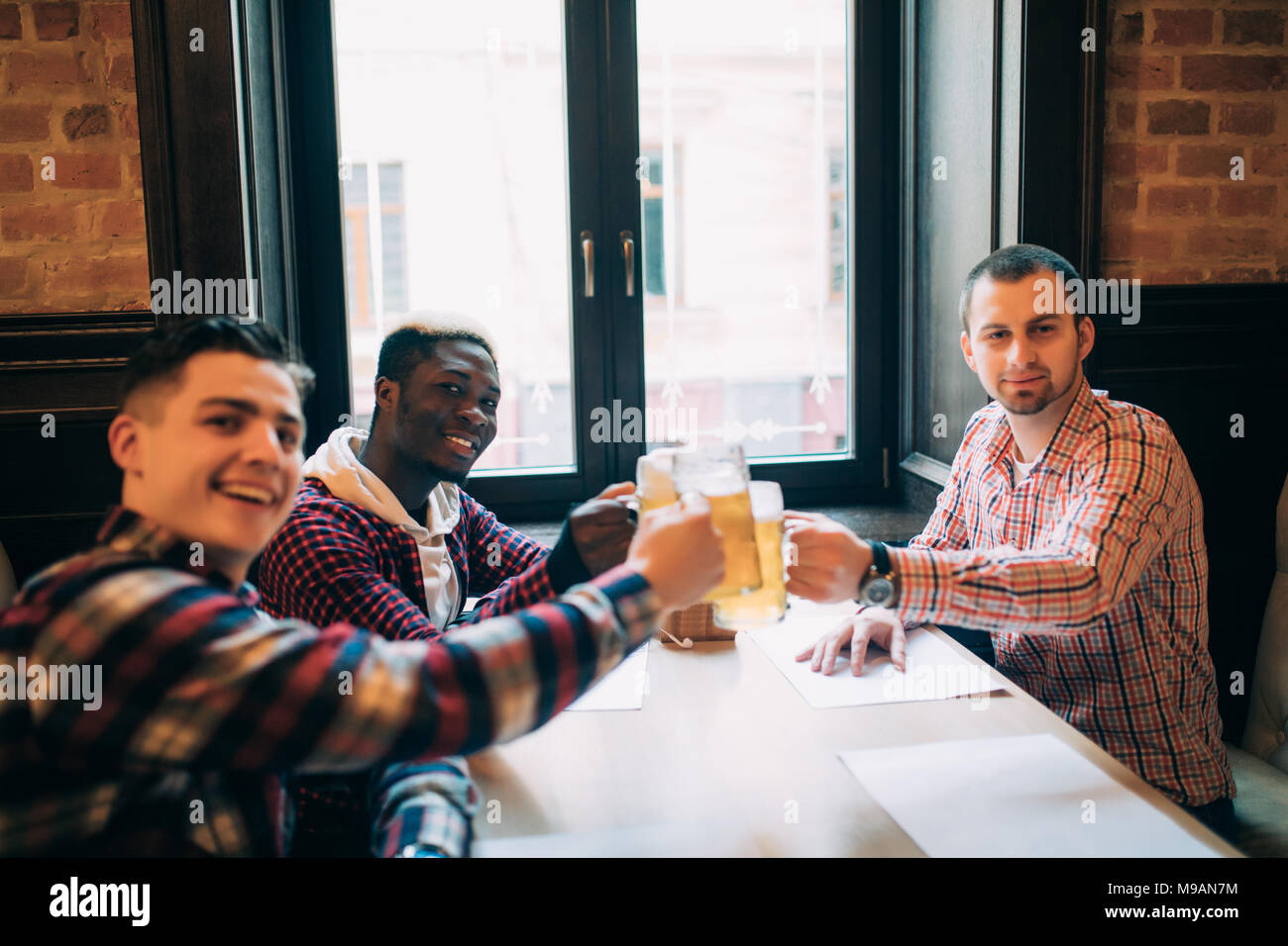 Handsome guys are talking and smiling while resting in pub Stock Photo ...