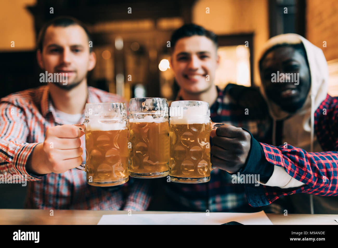 Happy male friends drinking beer and clinking glasses at bar or pub ...