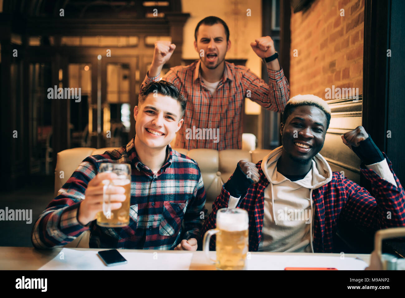Men at the pub watcing football game and drinking beer Stock Photo - Alamy