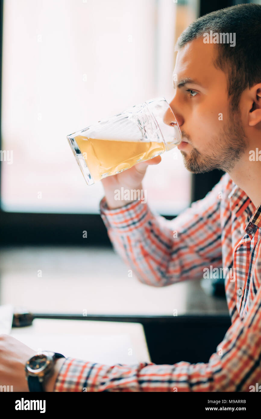 Man drinking beer. Side view of handsome young man drinking beer while ...