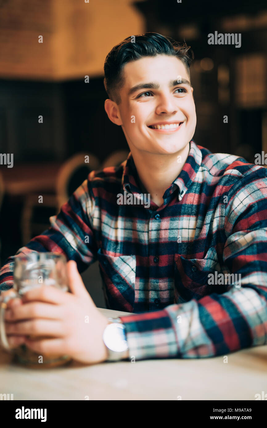 Young man sitting at bar counter with a pint of light beer Stock Photo ...