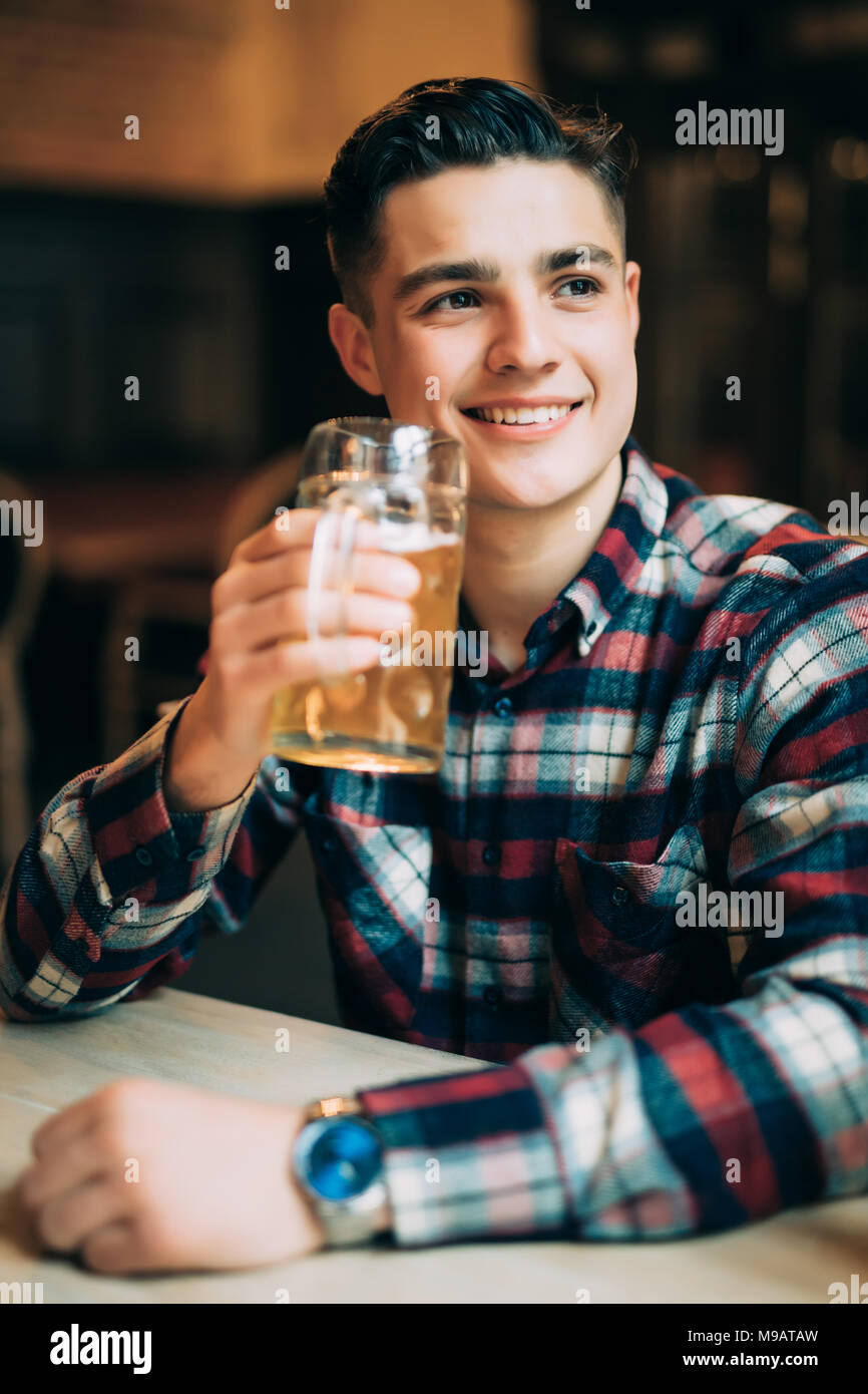 Young man sitting at bar counter with a pint of light beer Stock Photo ...