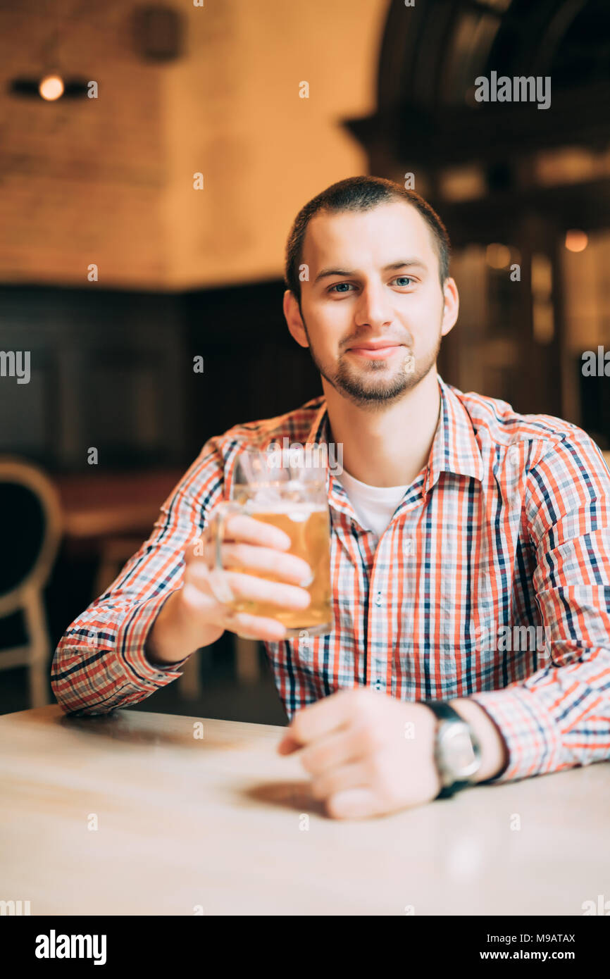 Handsome young man drinking light beer in a pub Stock Photo - Alamy