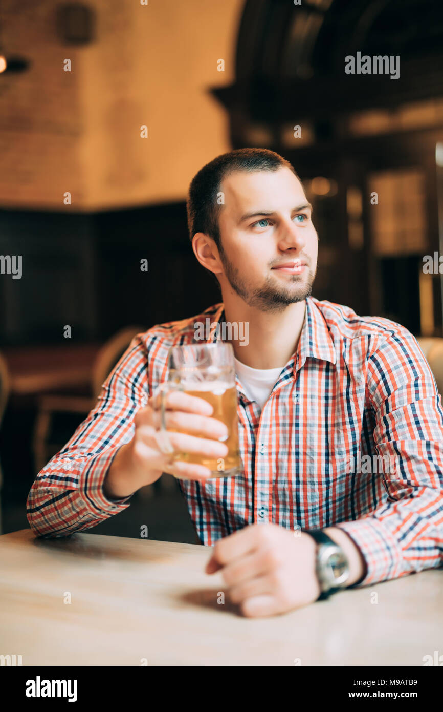 Handsome young man drinking light beer in a pub Stock Photo - Alamy