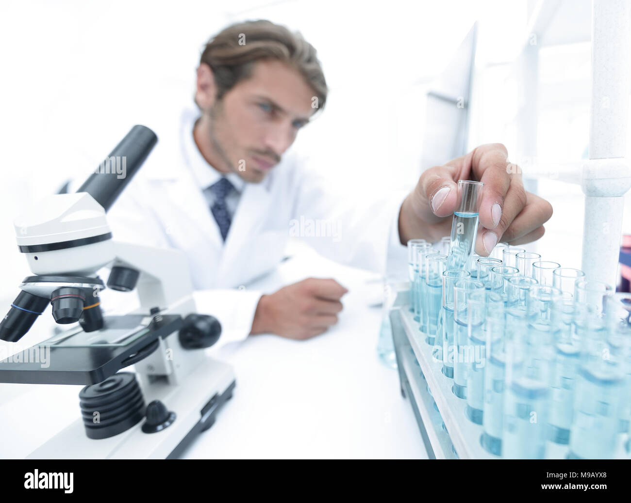 Chemist looking at test-tubes with blue liquids Stock Photo - Alamy