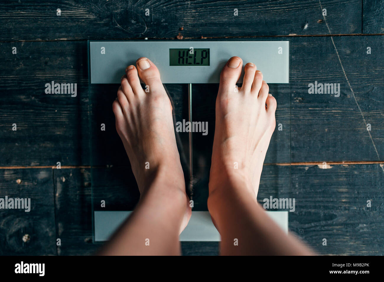 Female feet on the scales with inscription help Stock Photo - Alamy