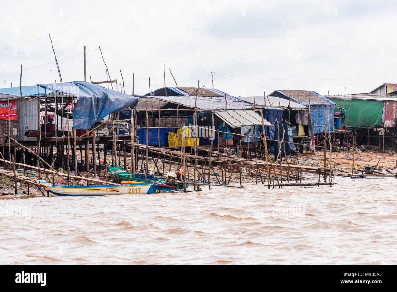 Houses with a boat jetty on bamboo stilts made from tarpaulin ...
