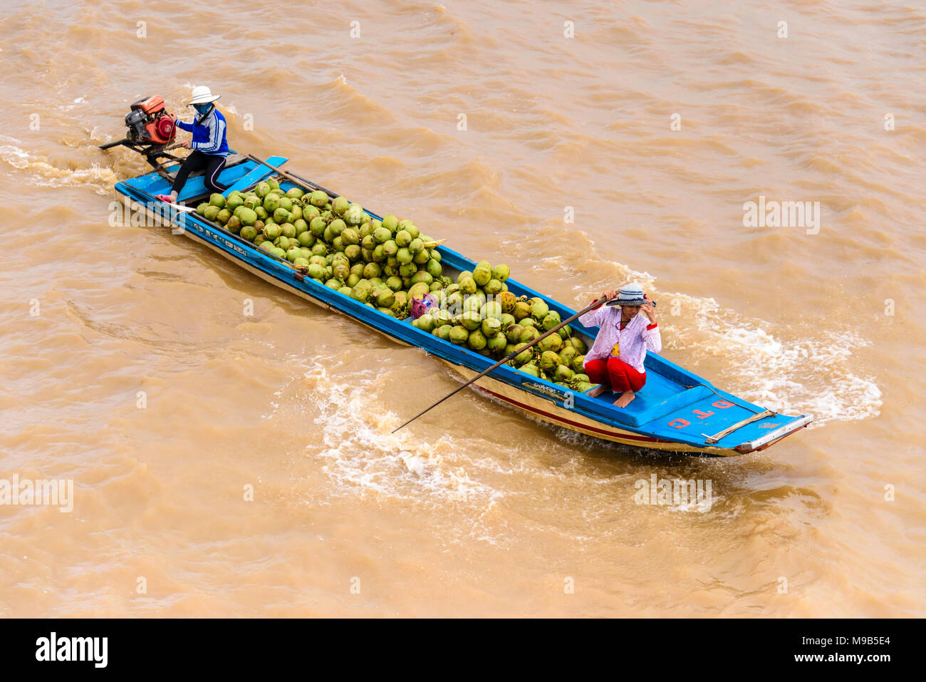Two Cambodian women bring a cargo of coconuts on a motorboat, Cambodia ...