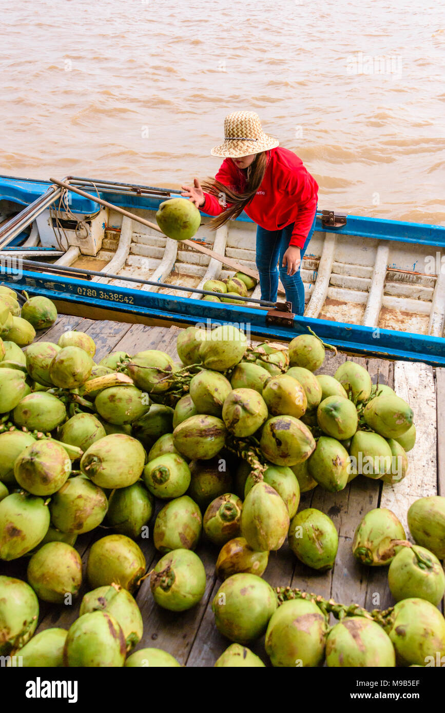 Women offload their cargo of coconuts from their wooden motorboat on ...