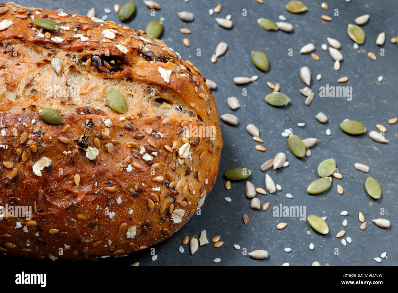 Close up of rustic whole grain bread loaf in baking tray on slate stone ...
