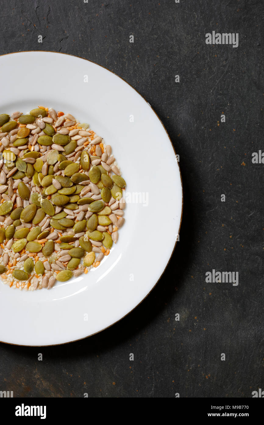 Various seeds on white plate on slate with copy space Stock Photo - Alamy