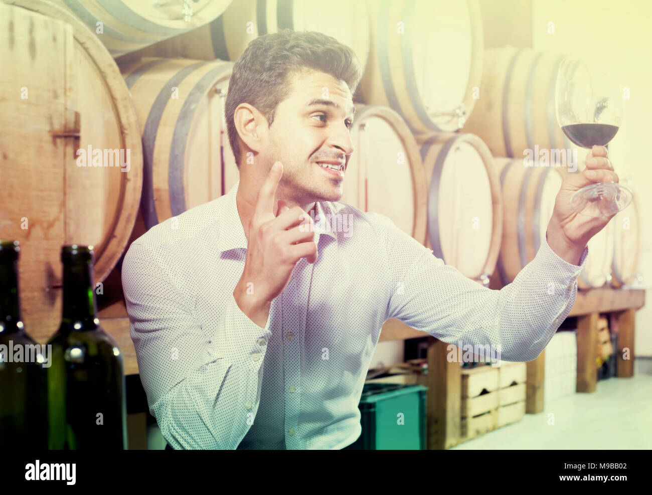 portrait of happy russian man tasting wine sample in glass in alcohol ...